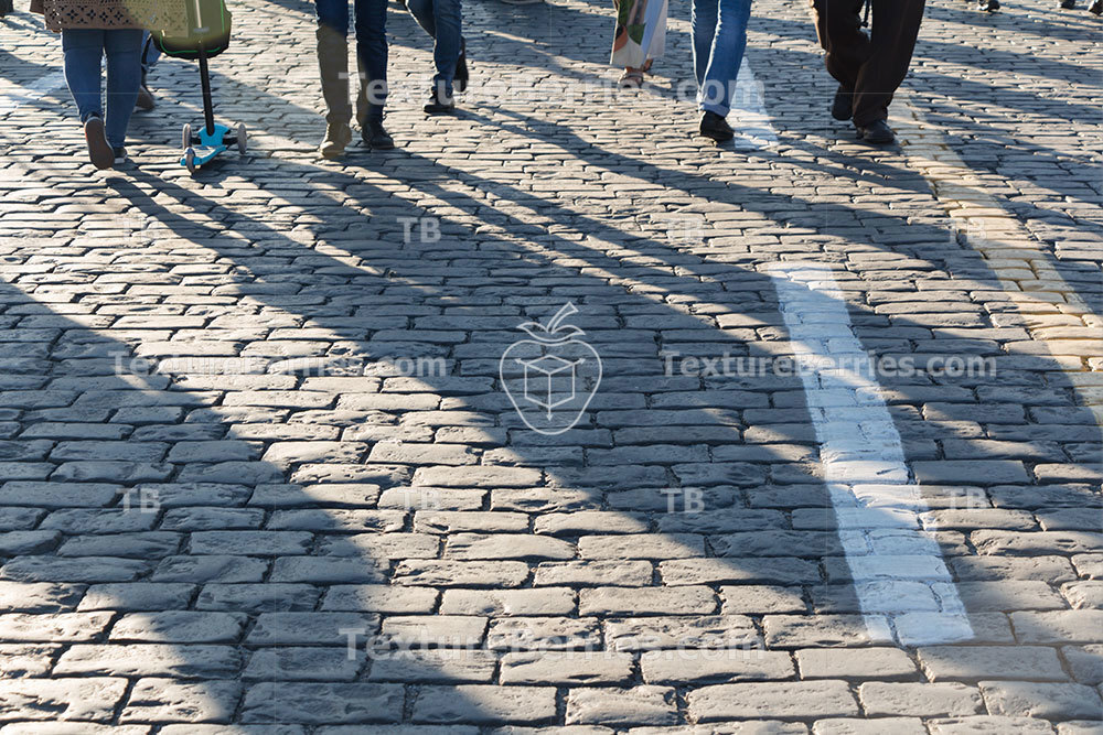 Pedestrians on cobblestone pavement, people traffic with shadows