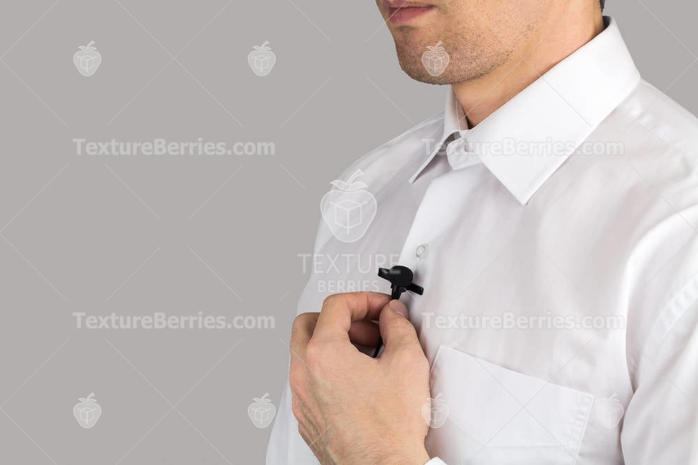 A man puts on lavalier microphone, interview, isolated on gray