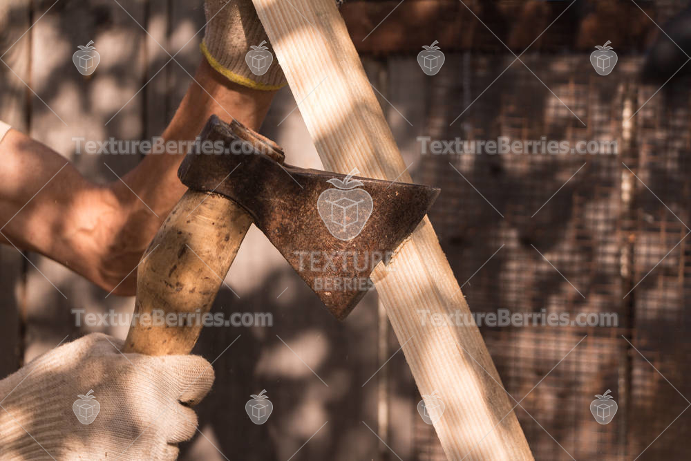 A carpenter with ax while planing wood plank