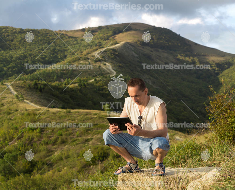 A man in the mountains with tablet computer, world wide web