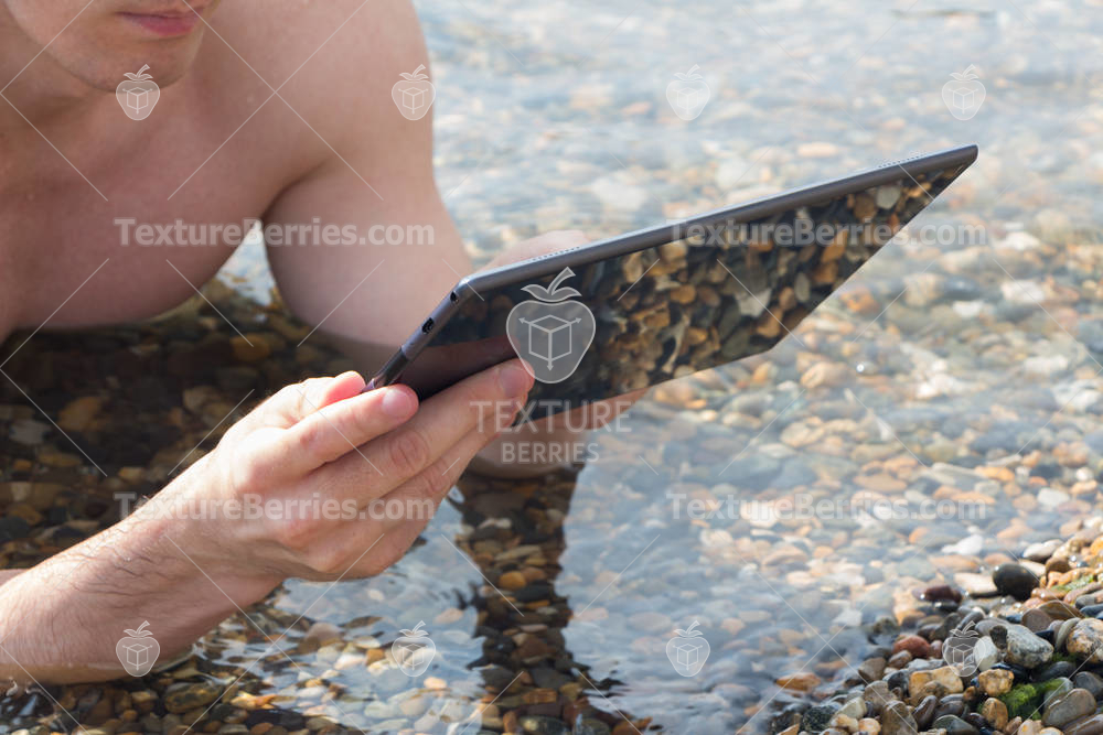 Work with tablet computer on pebble beach in the water